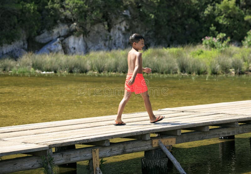 Boy Walking on a Wooden Foot Bridge on a Lake Stock Photo - Image of ...