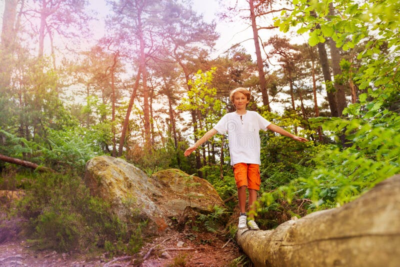 Boy Walks Over Log in the Forest Balance with Hand Stock Photo - Image ...