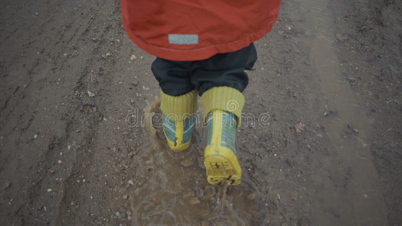 Boy Walks through the Puddles and Mud in the Spring. Stock Footage ...