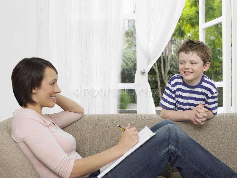 Boy Watching Mother Write Notes on Sofa Stock Photo - Image of ...