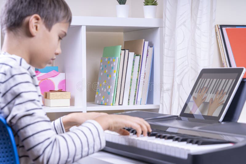 Boy Watching Video Lesson at Digital Tablet Computer and Playing Piano ...
