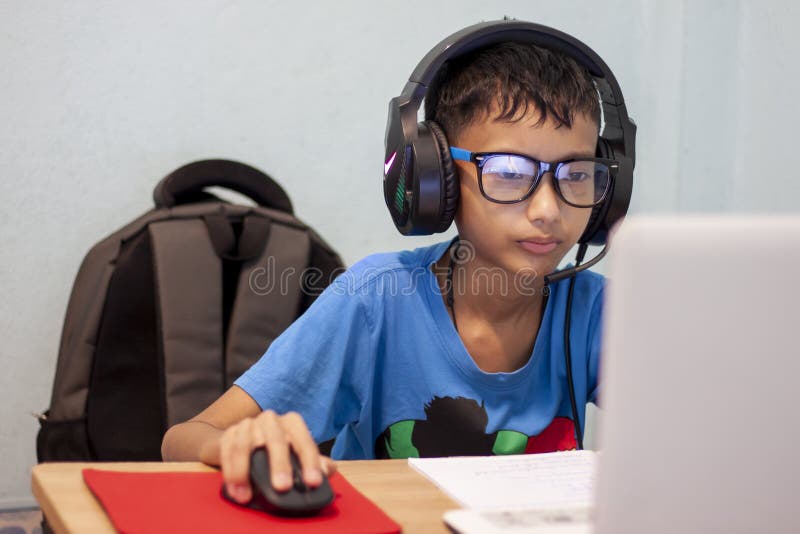 A Boy Wearing Headphones and Light Filtering Glasses is Using Laptops ...
