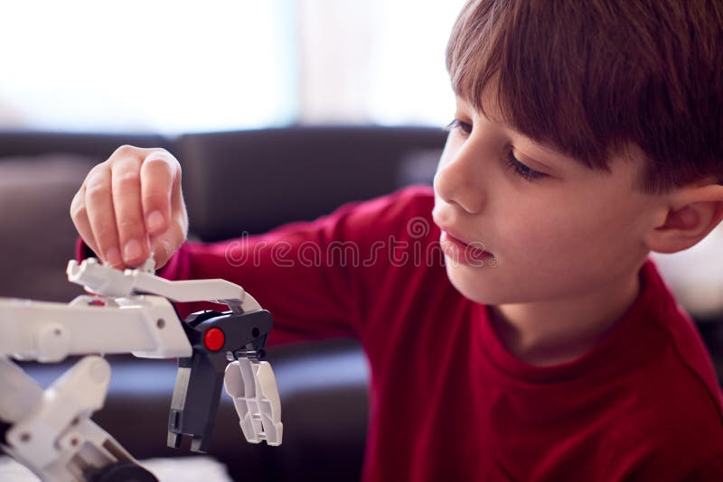 Boy Wearing Pyjamas Building Robotic Arm from Plastic Kit at Home Stock ...