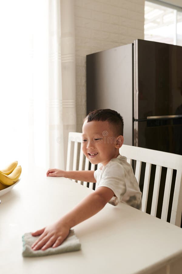 Boy Wiping Kitchen Table stock image. Image of happy - 245112487