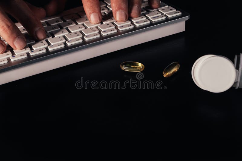 A Man Working at a Keyboard, There are Stress Pills on the Table Stock ...