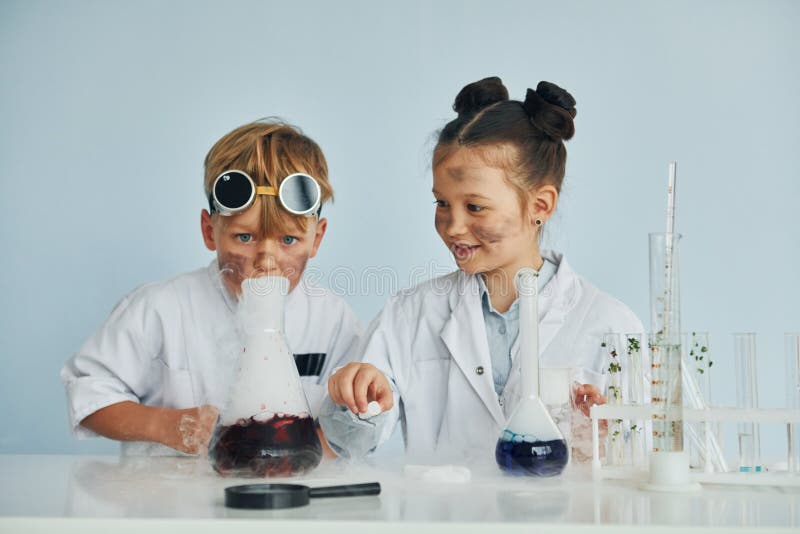 Boy Works with Liquid in Test Tubes. Children in White Coats Plays a ...