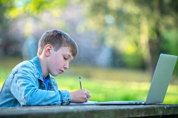 Boy is Writing Down Notes Outdoors. Scholar Studying Online with a ...