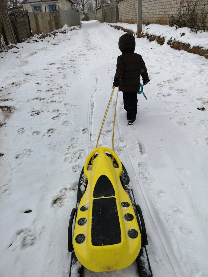 Boy with yellow sled stock photo. Image of yellow, snow - 202757634