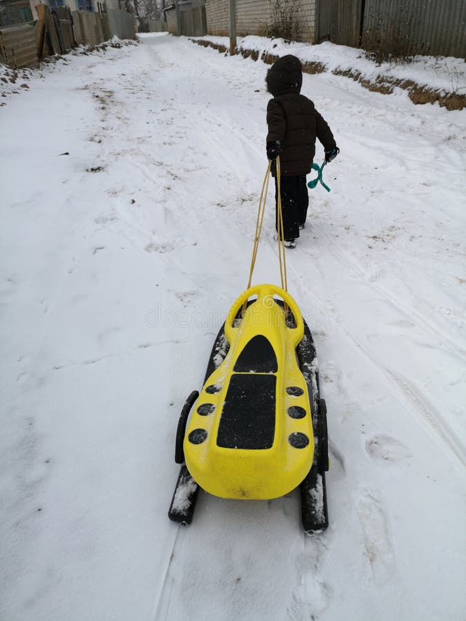 Boy with yellow sled stock photo. Image of footwear - 202757662