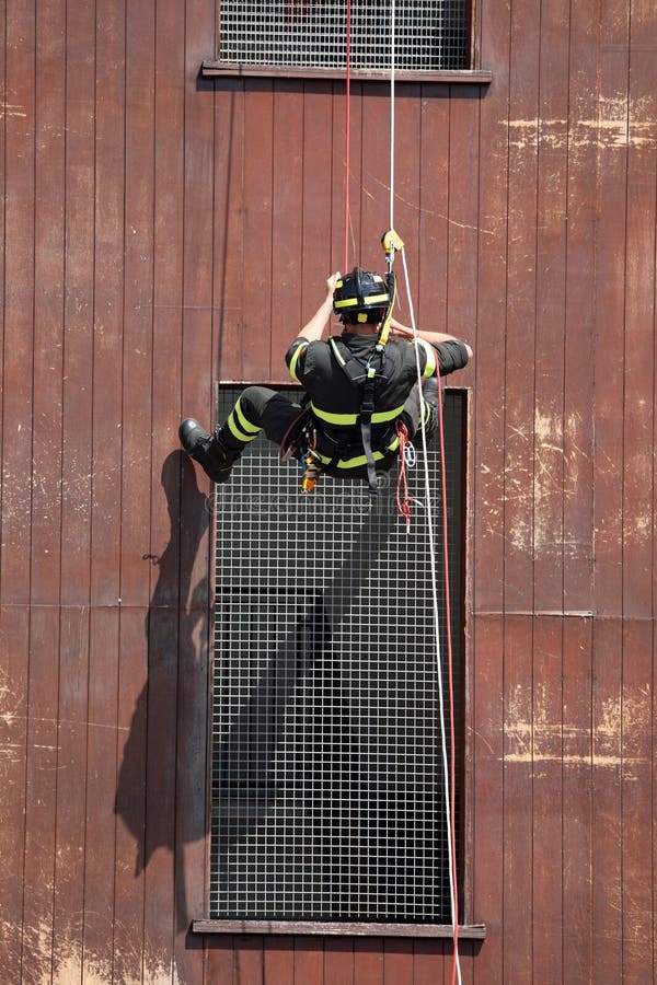 Brave Firefighter in Uniform and Protective Helmet Rappelling Down ...