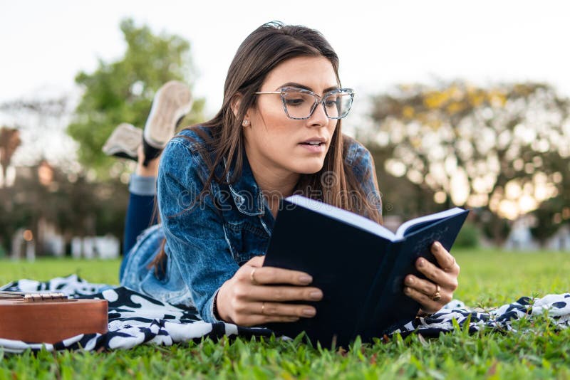 University Student Reading Book and Lying in the Grass Outside in the ...