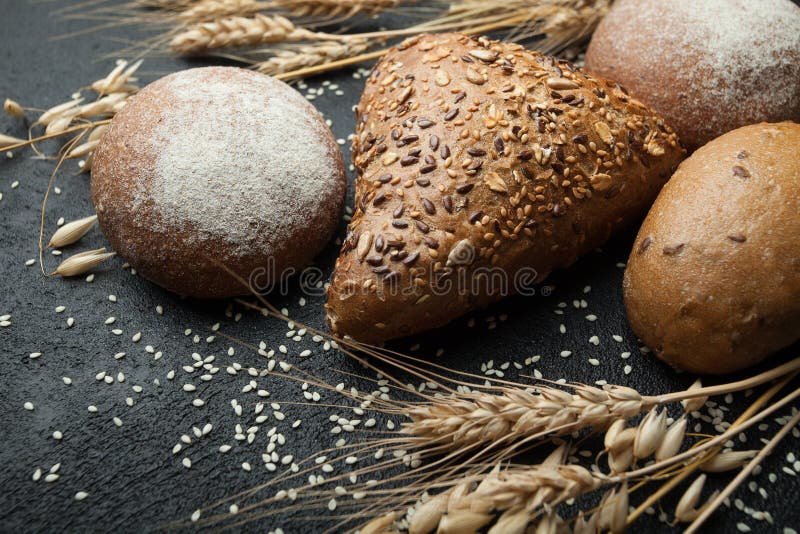 Bread of Different Kinds on a Dark Board with Spikelets of Wheat, Rye ...