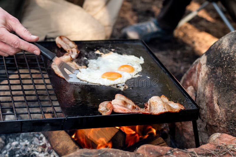 Breakfast Camp Cooking. Grilling Crispy Bacon and Eggs on a Cast Iron ...
