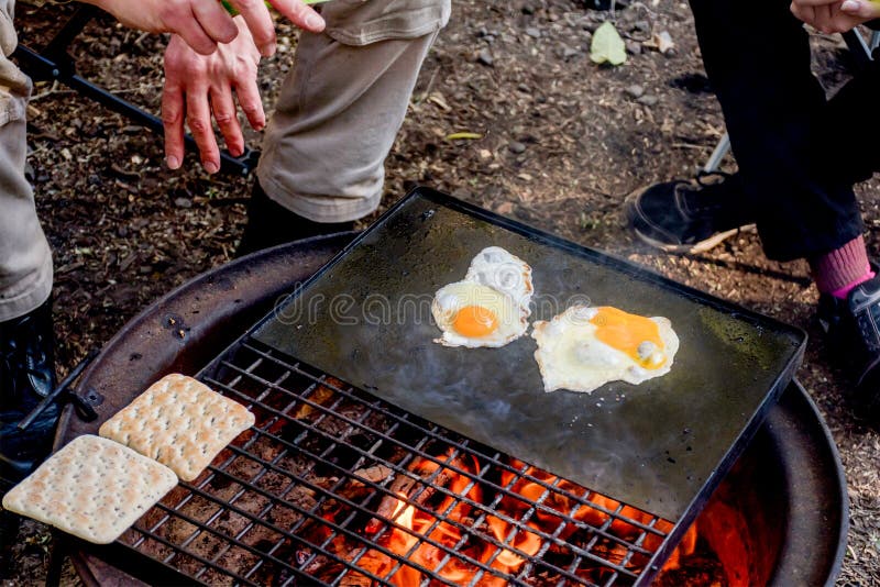 Breakfast Camp Cooking. Man Cooking Grilling Eggs and Warming Bread on ...