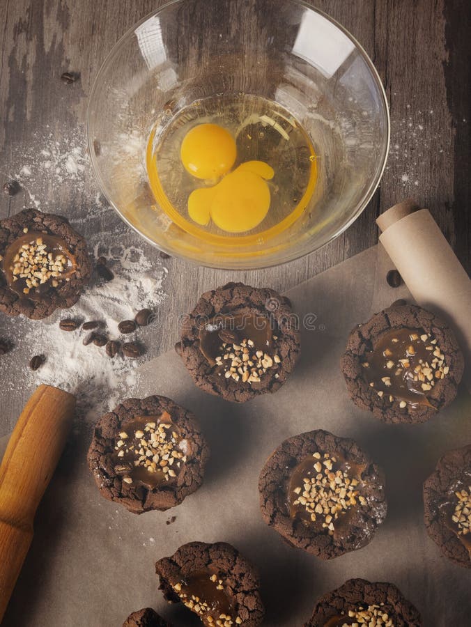 Breaking Eggs into a Bowl Next To Muffins on Baking Paper, Rolling Pin ...
