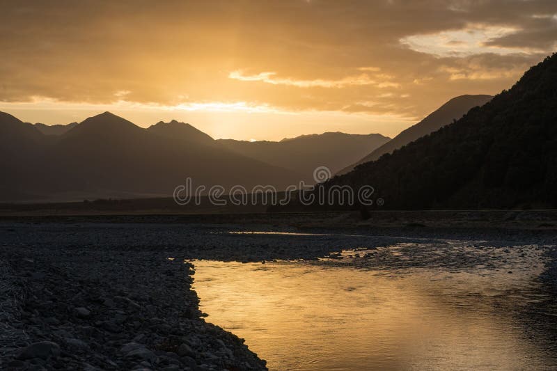 A Sunset Over Mountains with a River Flowing through it on the Side ...