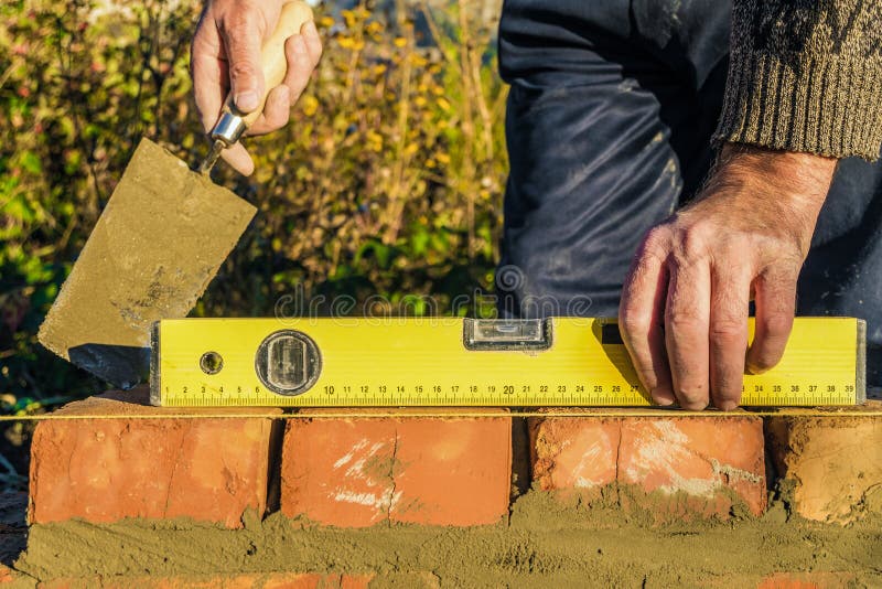 Bricklayer Checks the Horizontal Level of Brick Masonry Wall with a ...