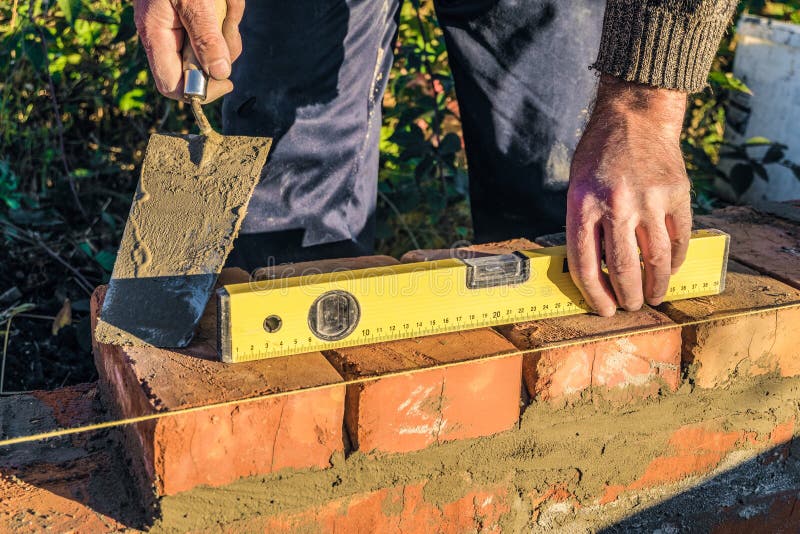 Bricklayer Checks the Horizontal Level of Brick Masonry Wall with a ...