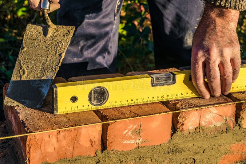 Bricklayer Checks the Horizontal Level of Brick Masonry Wall with a ...