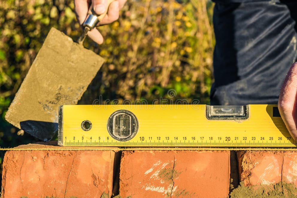 Bricklayer Checks the Horizontal Level of Brick Masonry Wall with a ...