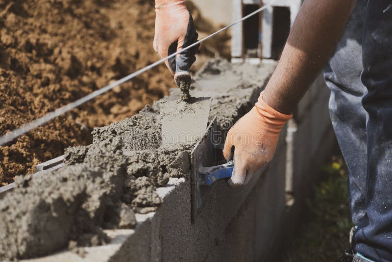 Bricklayer Spreading Concrete with a Trowel and Level To Build a Wall ...