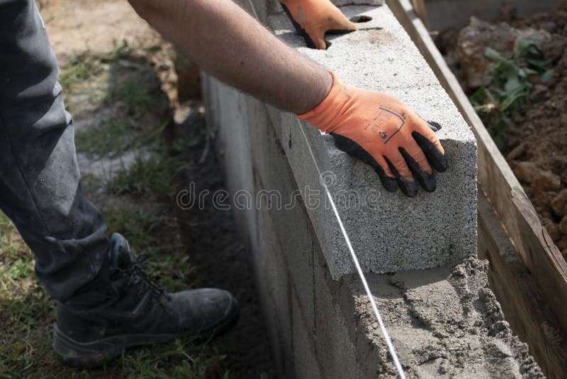 Bricklayer Spreading Concrete with a Trowel and Level To Build a Wall ...