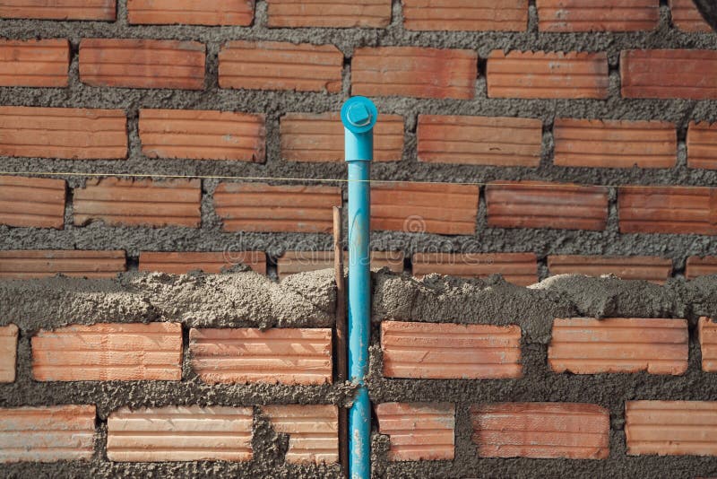 Bricklayer Installing Red Bricks Masonry and PVC Pipe in a New Wall ...