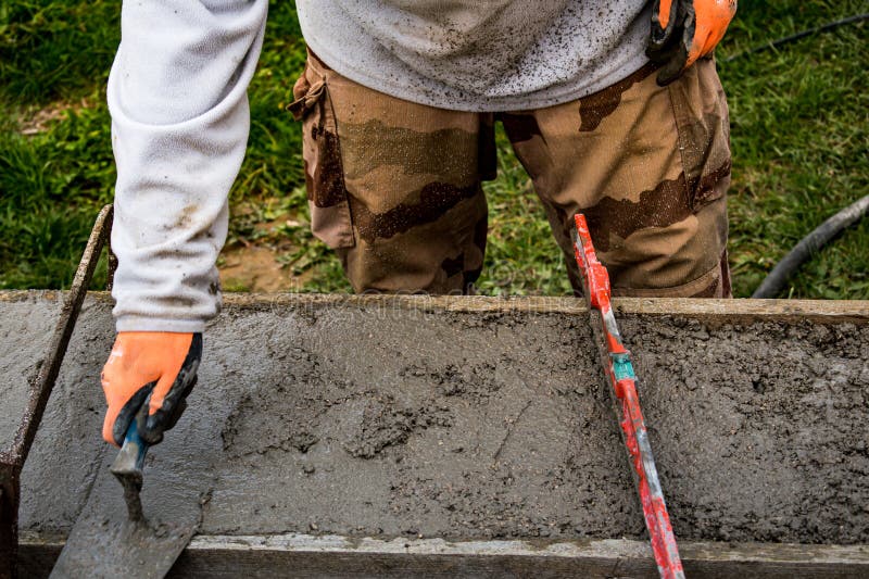 Bricklayer Spreading Concrete with a Trowel and Level To Build a Wall ...