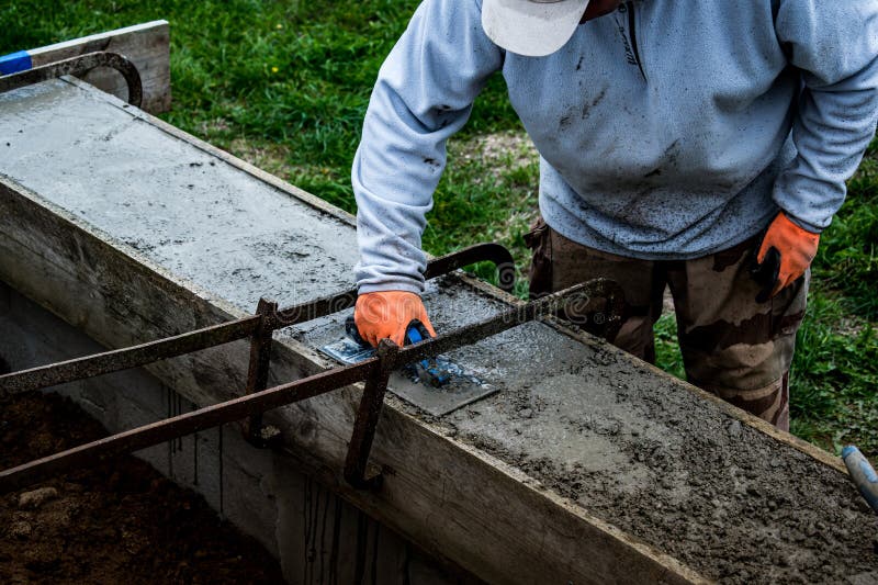 Bricklayer Spreading Concrete with a Trowel and Level To Build a Wall ...