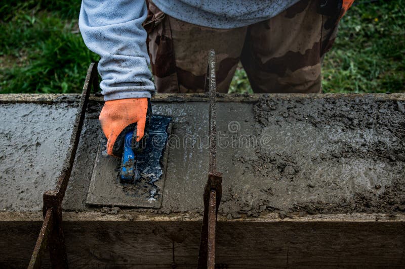 Bricklayer Spreading Concrete with a Trowel and Level To Build a Wall ...