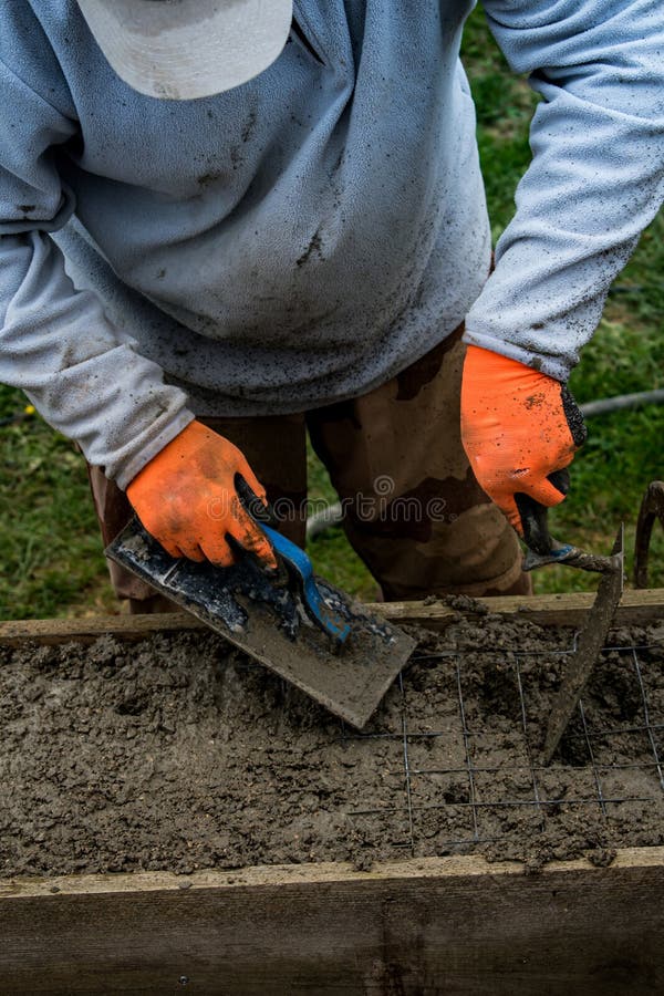 Bricklayer Spreading Concrete with a Trowel and Level To Build a Wall ...