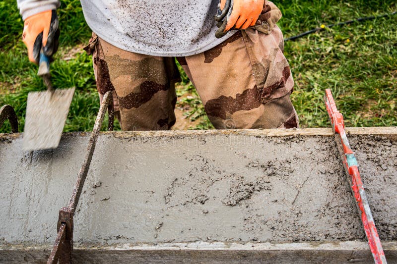 Bricklayer Spreading Concrete with a Trowel and Level To Build a Wall ...