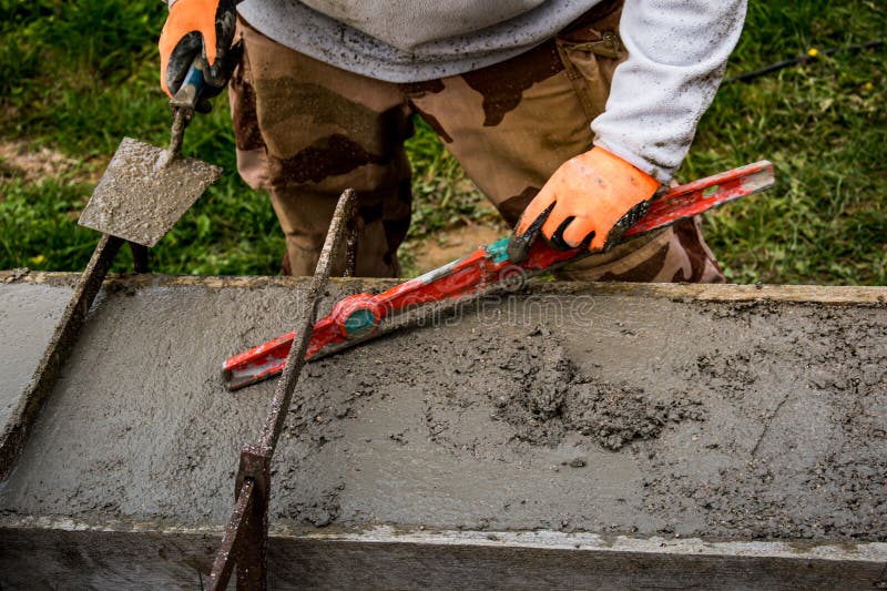 Bricklayer Spreading Concrete with a Trowel and Level To Build a Wall ...