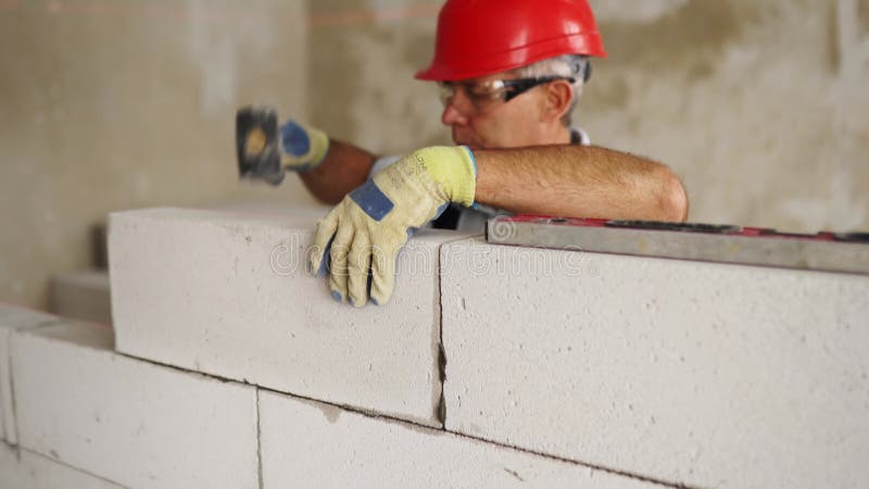 Bricklayer Using Rubber Mallet Hammer To Tap and Level Concrete Blocks ...