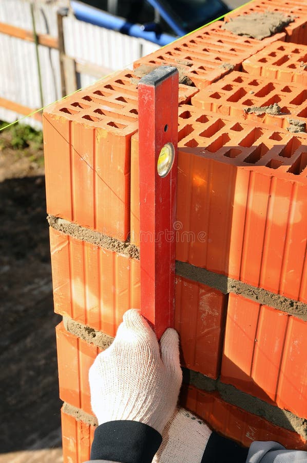 Bricklayer Using a Spirit Level To Check New Brick Wall. Bricklaying ...