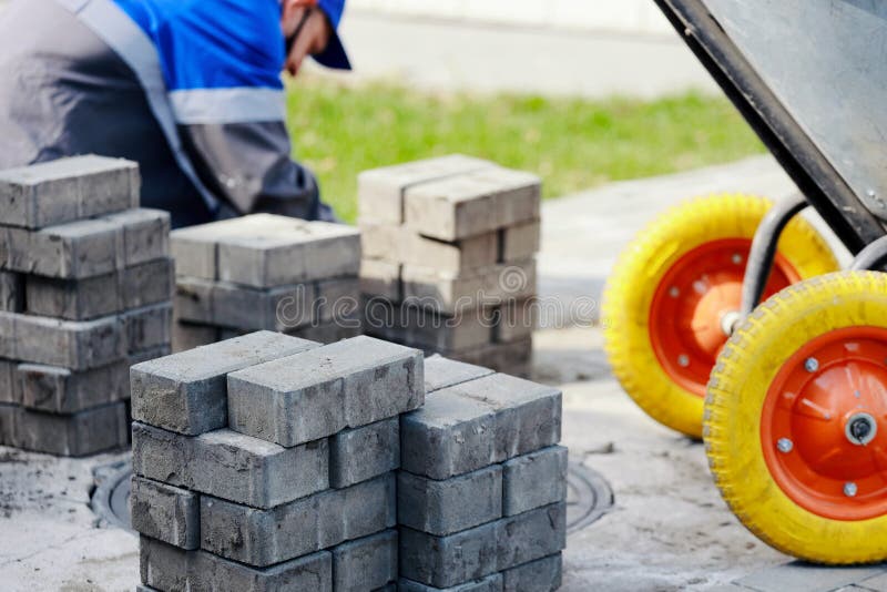 Bricklayer in Work Clothes Sits on Sidewalk and Lays Out Paving Slabs ...