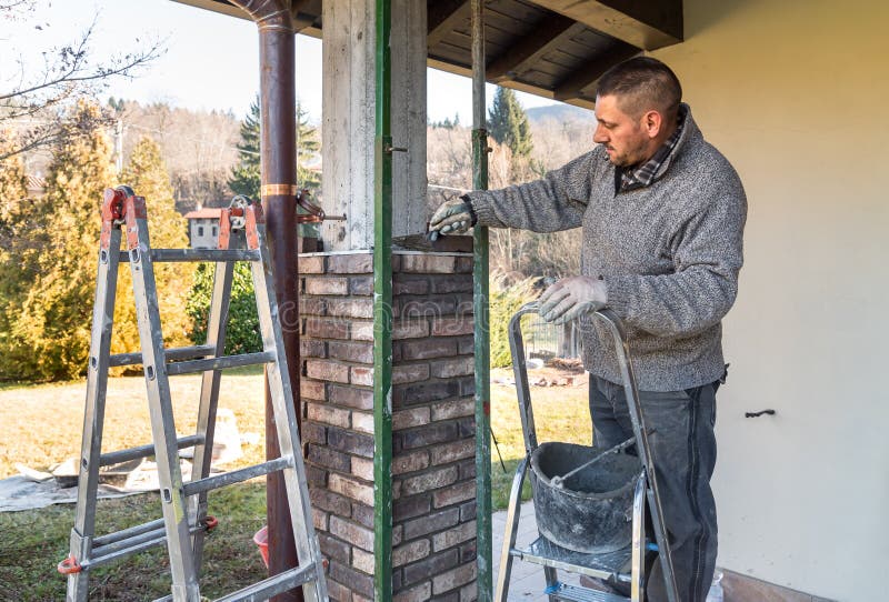 Bricklayer Worker Installing Bricks on the Exterior Concrete Pillar of ...