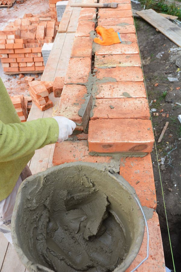 Bricklaying. Bricklayer Worker Installing Red Blocks and Caulking Brick ...