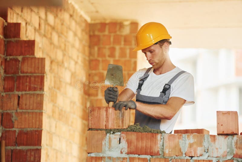 Bricks Installation. Young Man Working in Uniform at Construction at ...