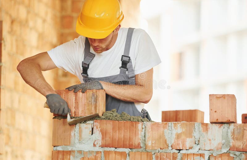 Bricks Installation. Young Man Working in Uniform at Construction at ...