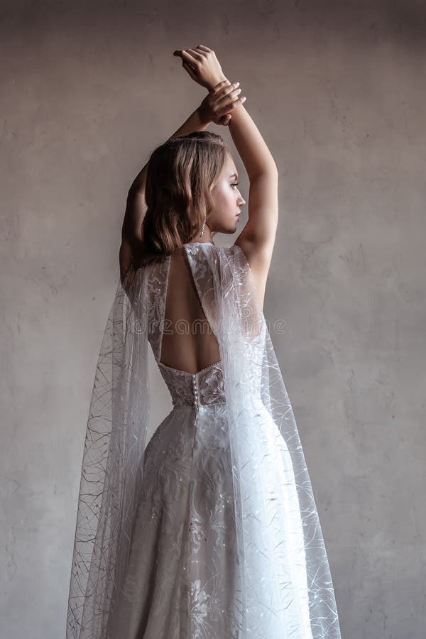Bride in a Beautiful Wedding Dress Raises Her Hands. Back View Stock ...