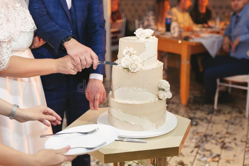 The Bride and Groom Cut a Gorgeous Wedding Cake at a Banquet. Stock ...