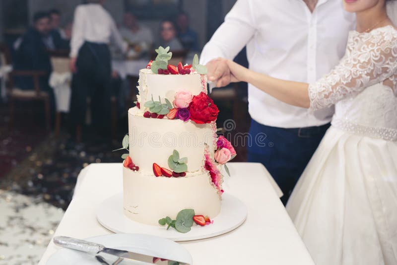 The Bride and Groom Cut a Gorgeous Wedding Cake at a Banquet. Stock ...