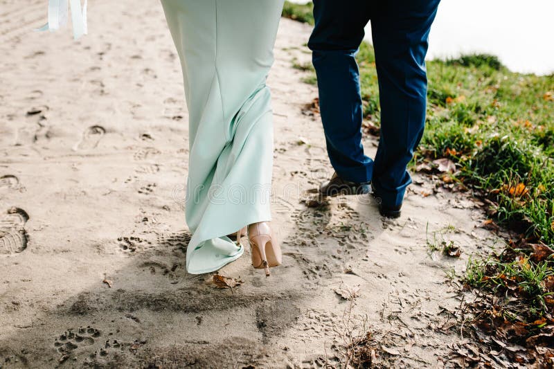 The Bride and Groom Go Back on the Sand on the Beach. Close Up Stock ...