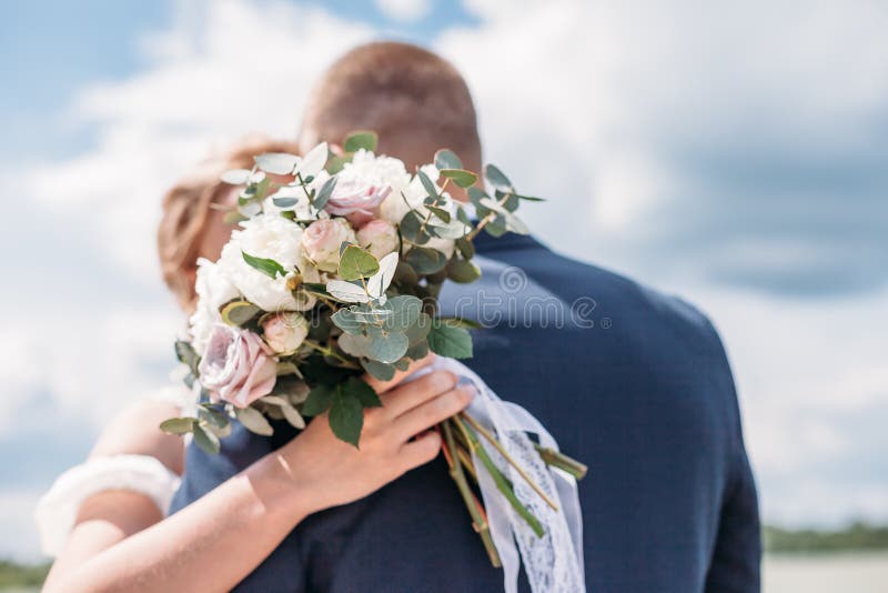 Bride and Groom Hugging from Behind Wedding Bouquet Closeup Stock Photo ...
