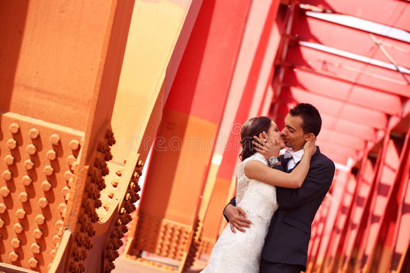 Bride and Groom Kissing on a Red Bridge Stock Photo - Image of bouquet ...