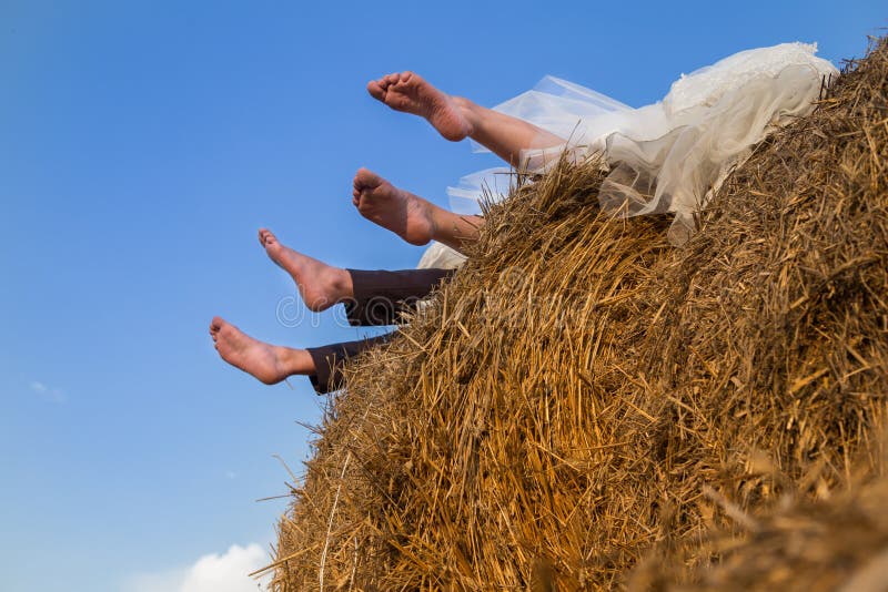 Feet of the Bride and Groom Stick Out of a Stack of Straw Stock Photo ...