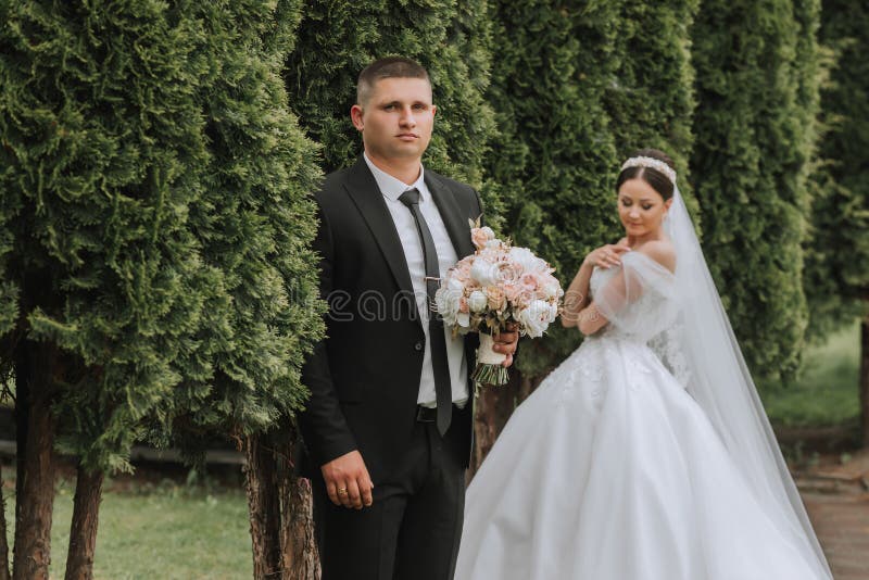The Bride and Groom Pose Against the Background of Green Trees Stock ...