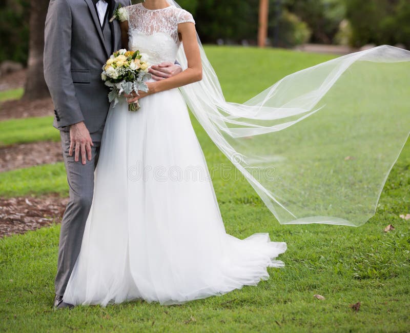 Bride and Groom Pose with Flowing Veil Stock Photo - Image of ...
