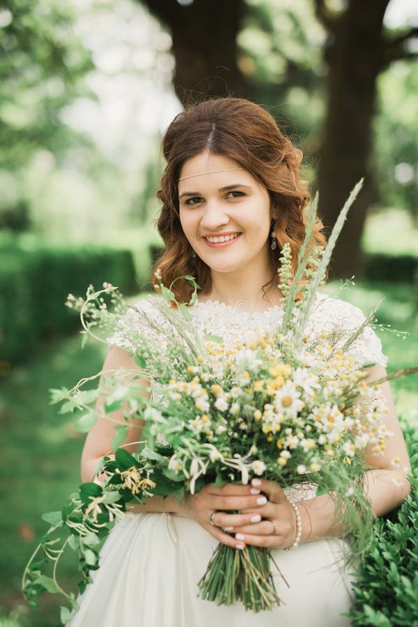 The Bride Holding Bouquet of Flowers in Park. Wedding Stock Photo ...